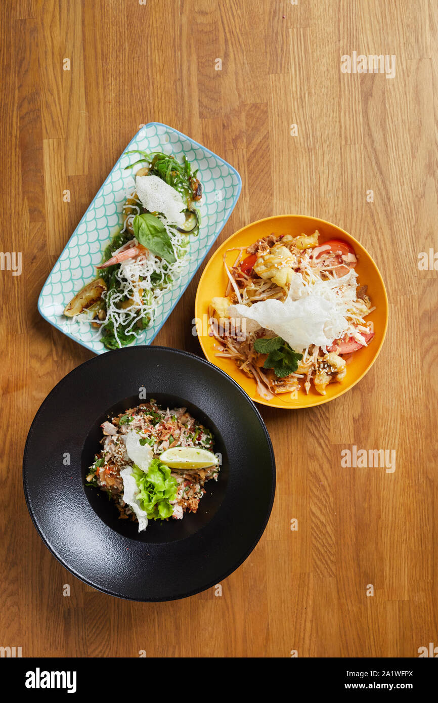 Above view background of three Asian dishes set on wooden table in cafe ...