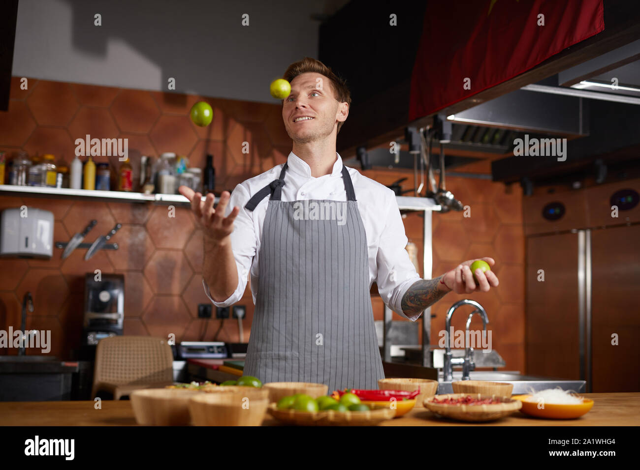Waist up portrait of handsome professional chef juggling limes while ...