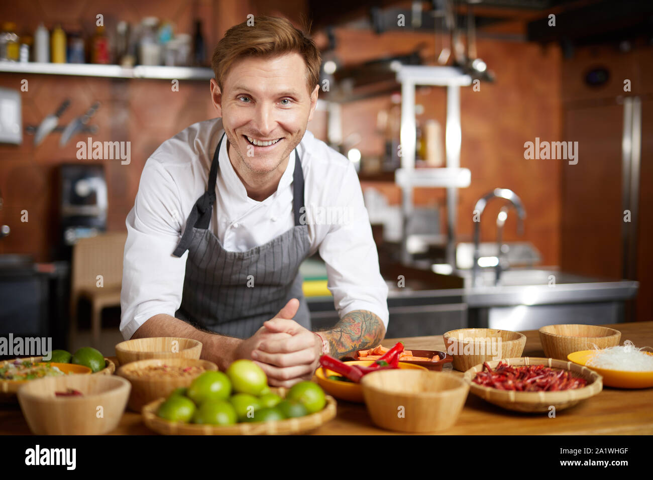 Portrait of contemporary chef smiling at camera while posing with ...
