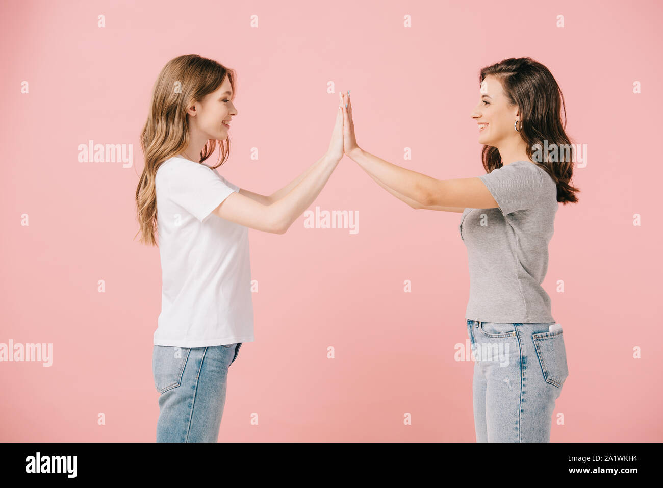 side view of attractive and smiling women in t-shirts giving high five ...