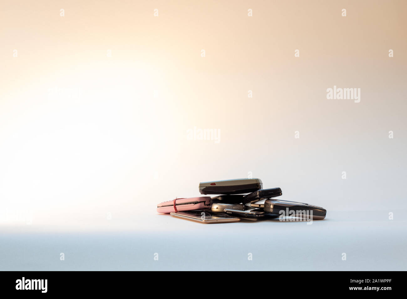 collection of old mobile phones stacked, piled in front of white ...