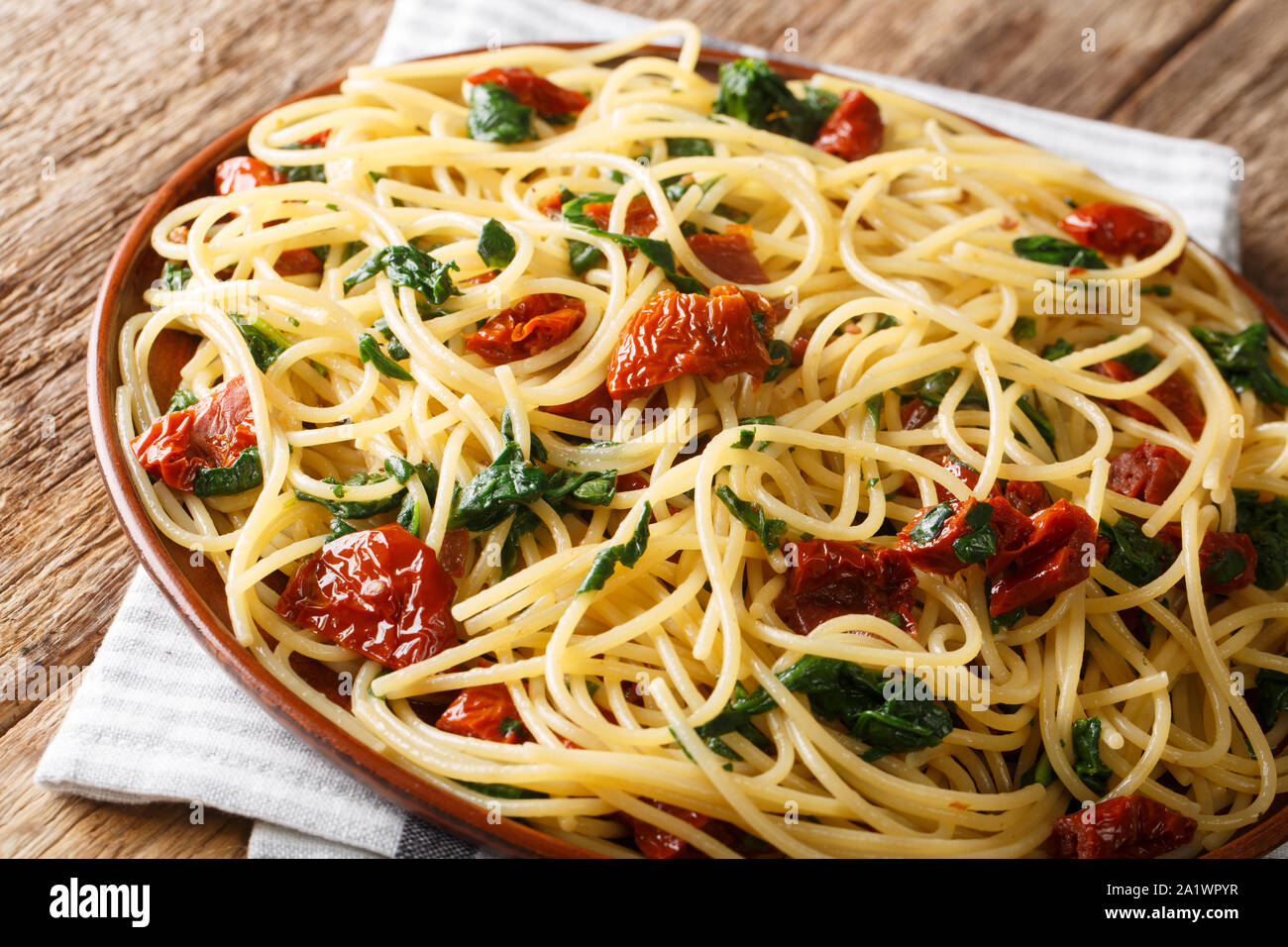 Side dish of spaghetti with dried tomatoes, cheese and spinach close-up ...