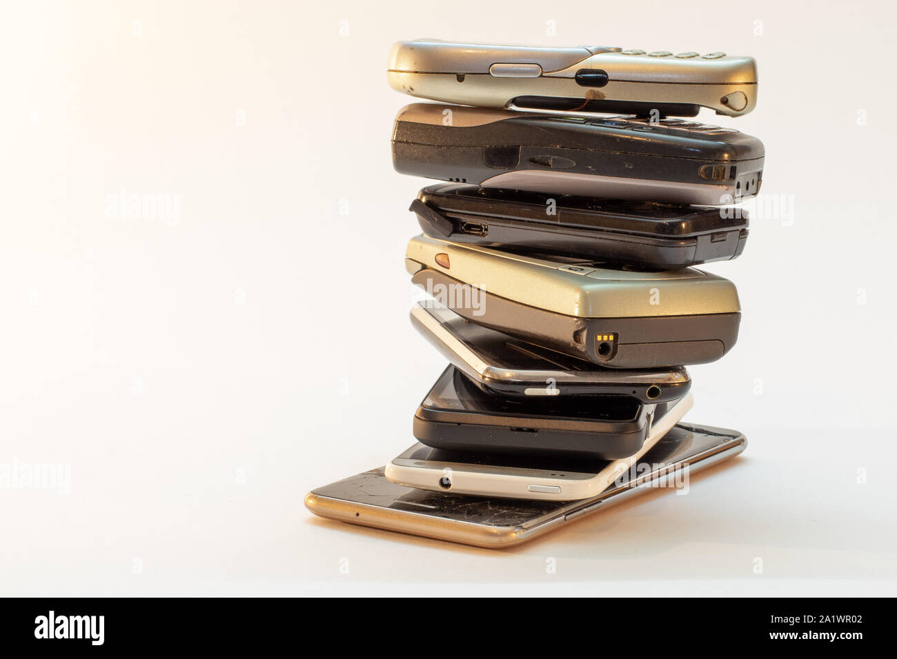 collection of old mobile phones stacked, piled in front of white ...