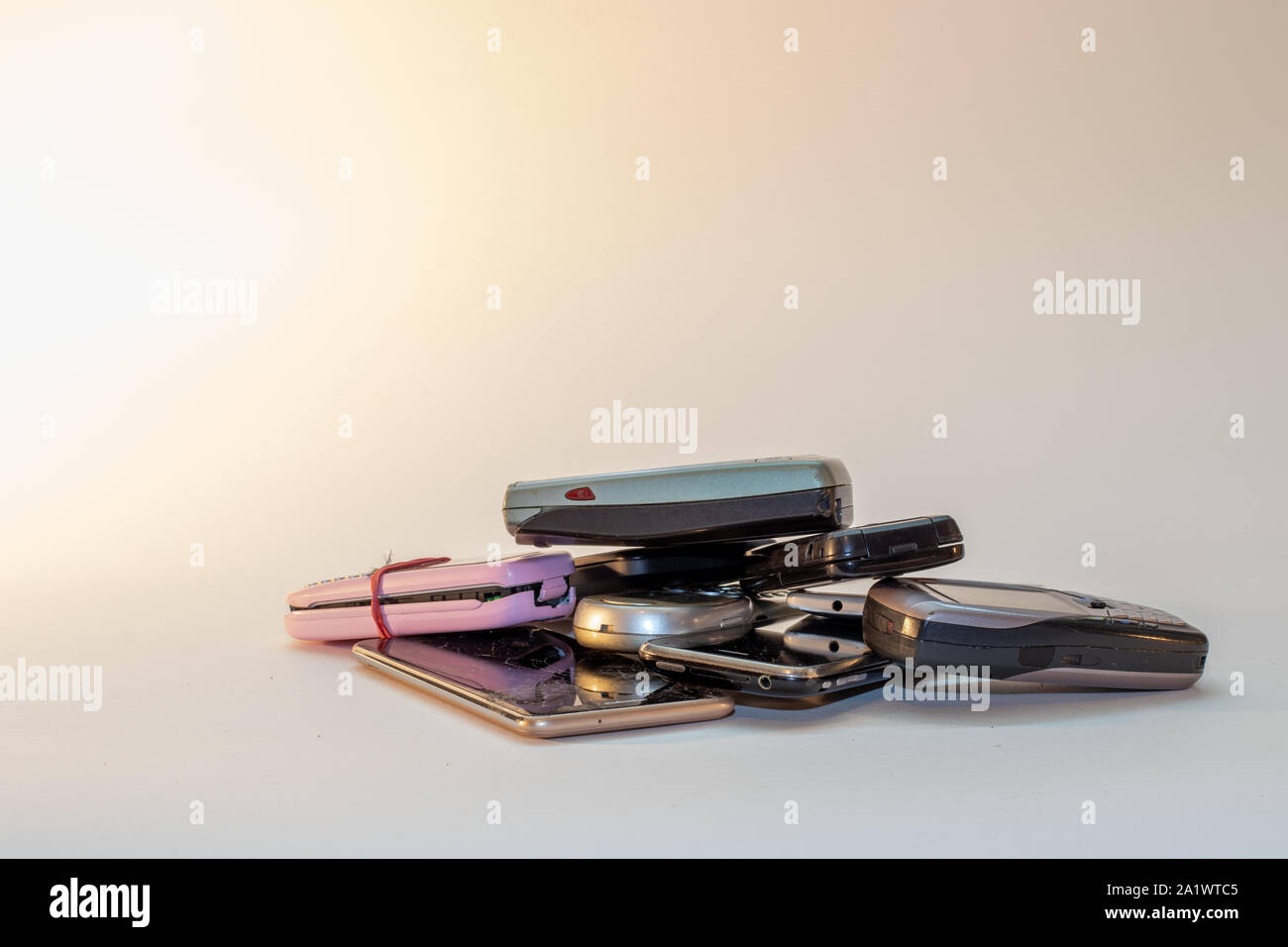collection of old mobile phones stacked, piled in front of white ...