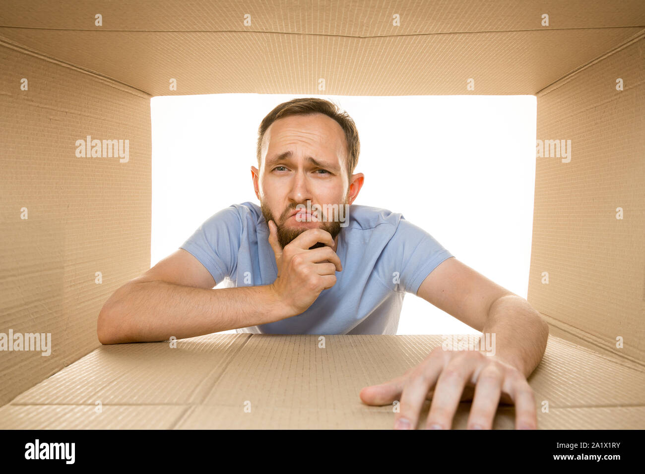 Young sad man opening the biggest postal package isolated on white ...