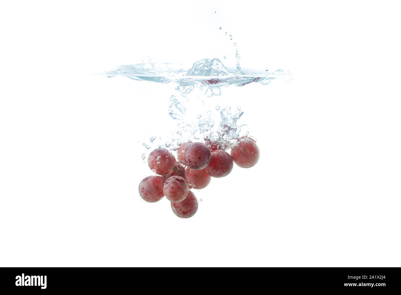 Isolated Red grapes splashing and sinking in water on white background ...