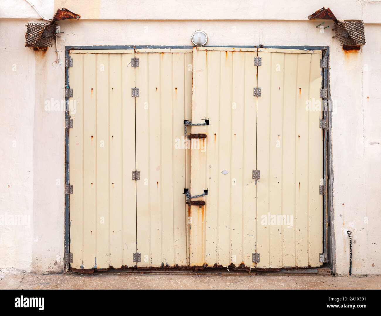 Old yellow metal gate in stone wall, front view Stock Photo - Alamy