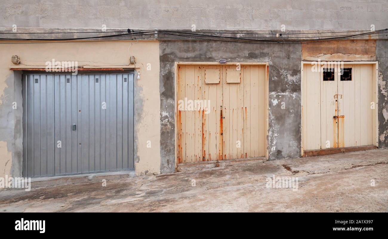 Three closed gates in a row in grungy concrete wall, old port building ...