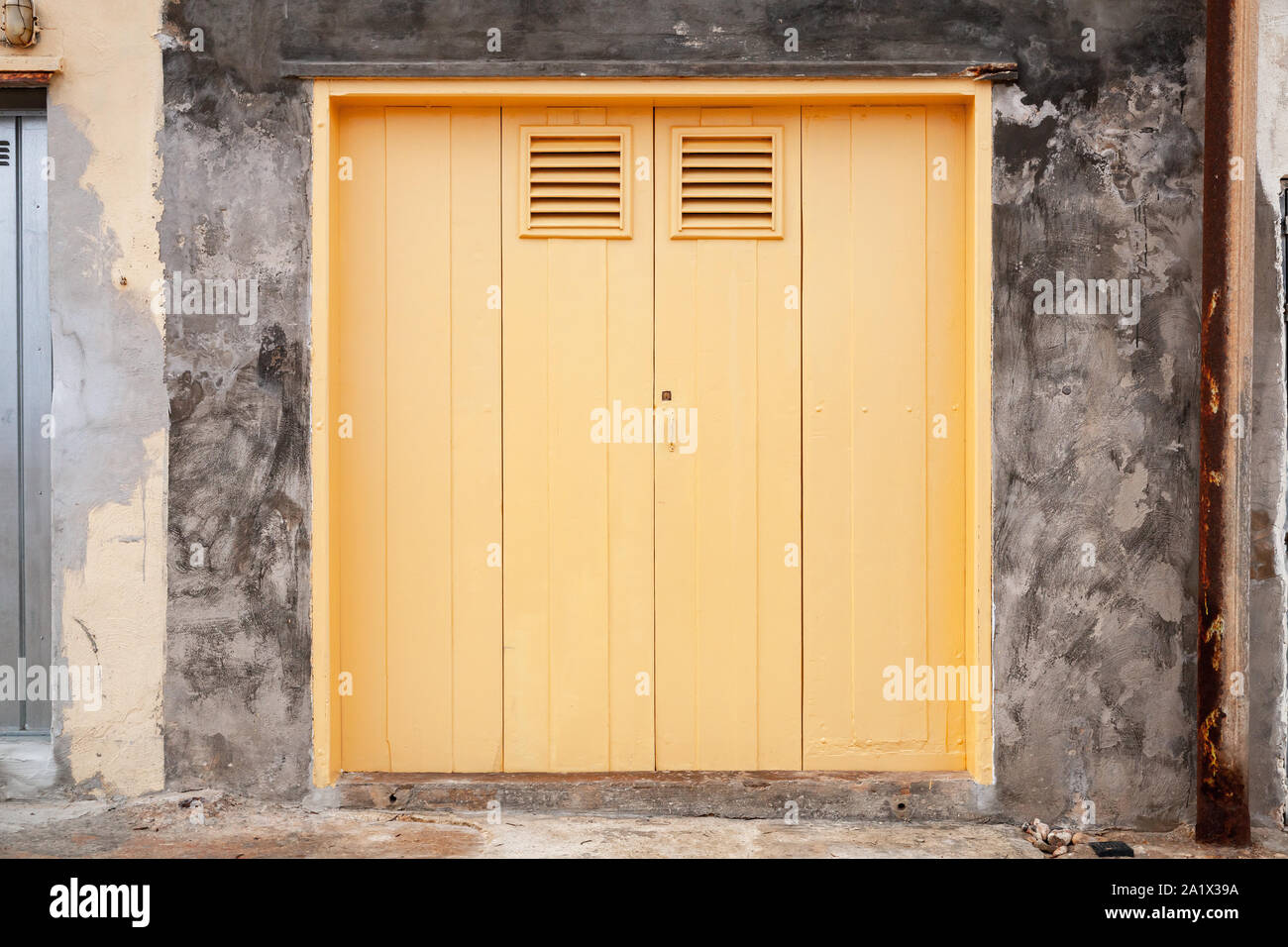 Closed old yellow gate in grungy stone wall, front view Stock Photo - Alamy