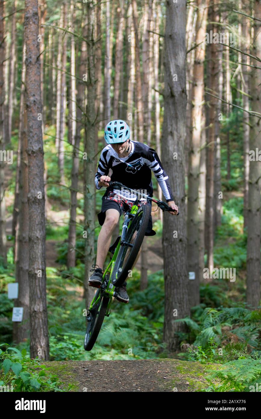 Teenage boy leaping around on a mountain biking on Kinver Edge forest ...
