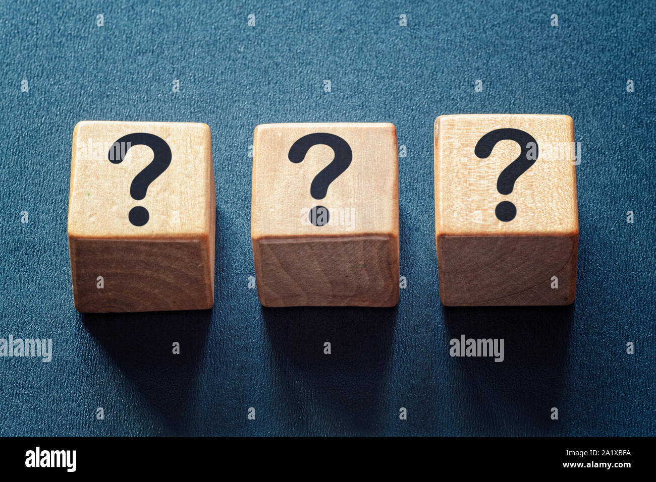 Row of three question marks on wooden blocks viewed high angle centered ...