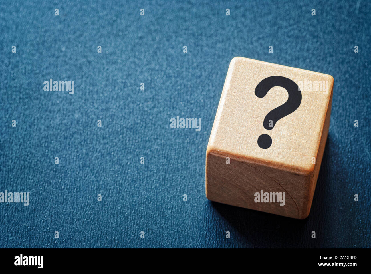 Wooden toy cube with a question mark viewed high angle on a textured ...