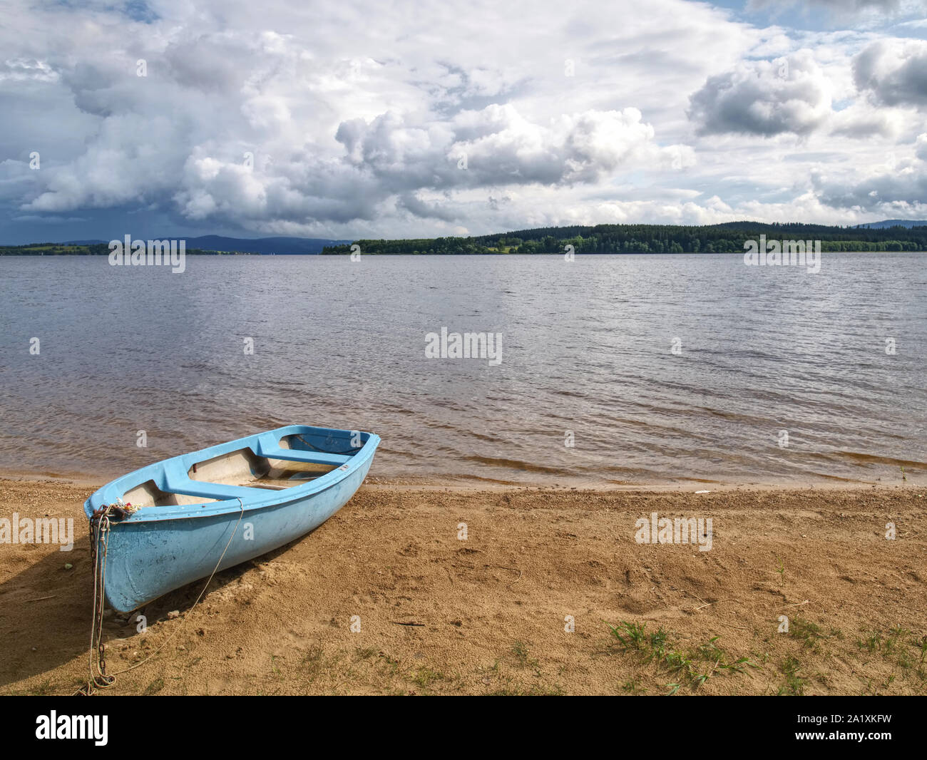 Low angle view to anchored laminate blue rowing boat at large lake with ...