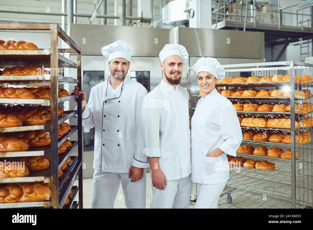 Bakers on the background of trays with breads in a bakery Stock Photo ...