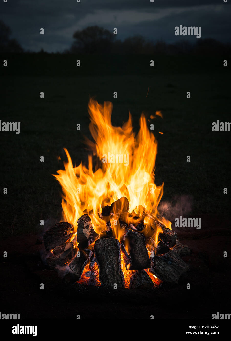 A close up of a roaring log fire at night with bright orange flames ...