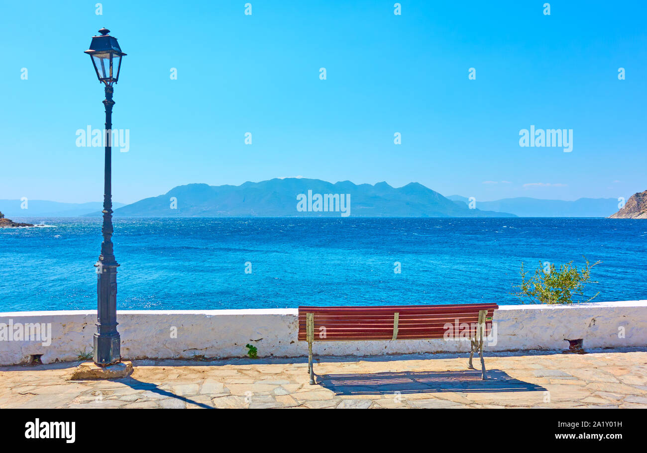 Sea and waterfront with bench and retro lamppost in Perdika fishing ...