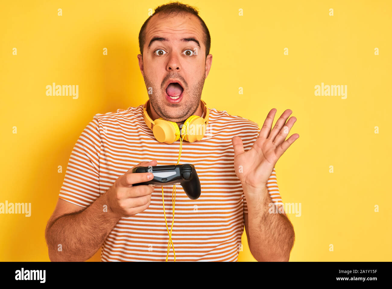 Young gamer man playing video game using headphones over isolated ...