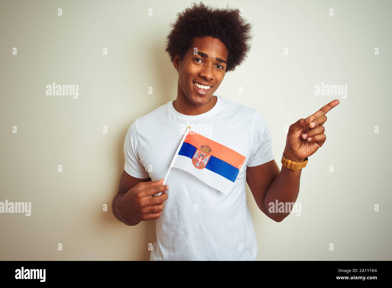 Young afro american man holding Serbia Serbian flag standing over ...