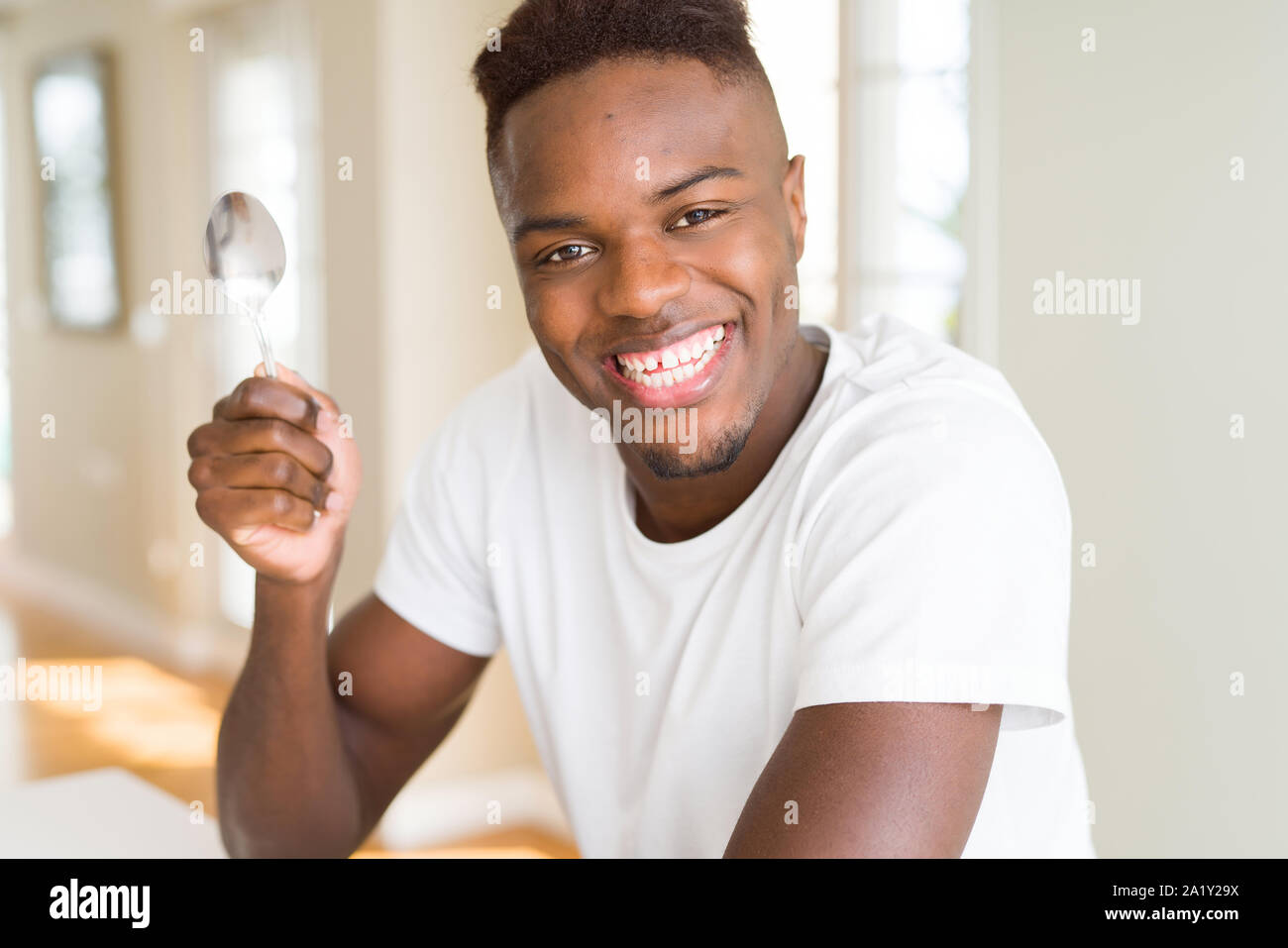 Handsome african man holding silver spoon smiling Stock Photo - Alamy