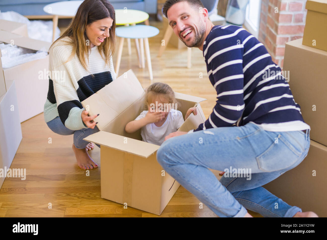 Beautiful famiily, kid playing with his parents riding cardboard fanny ...