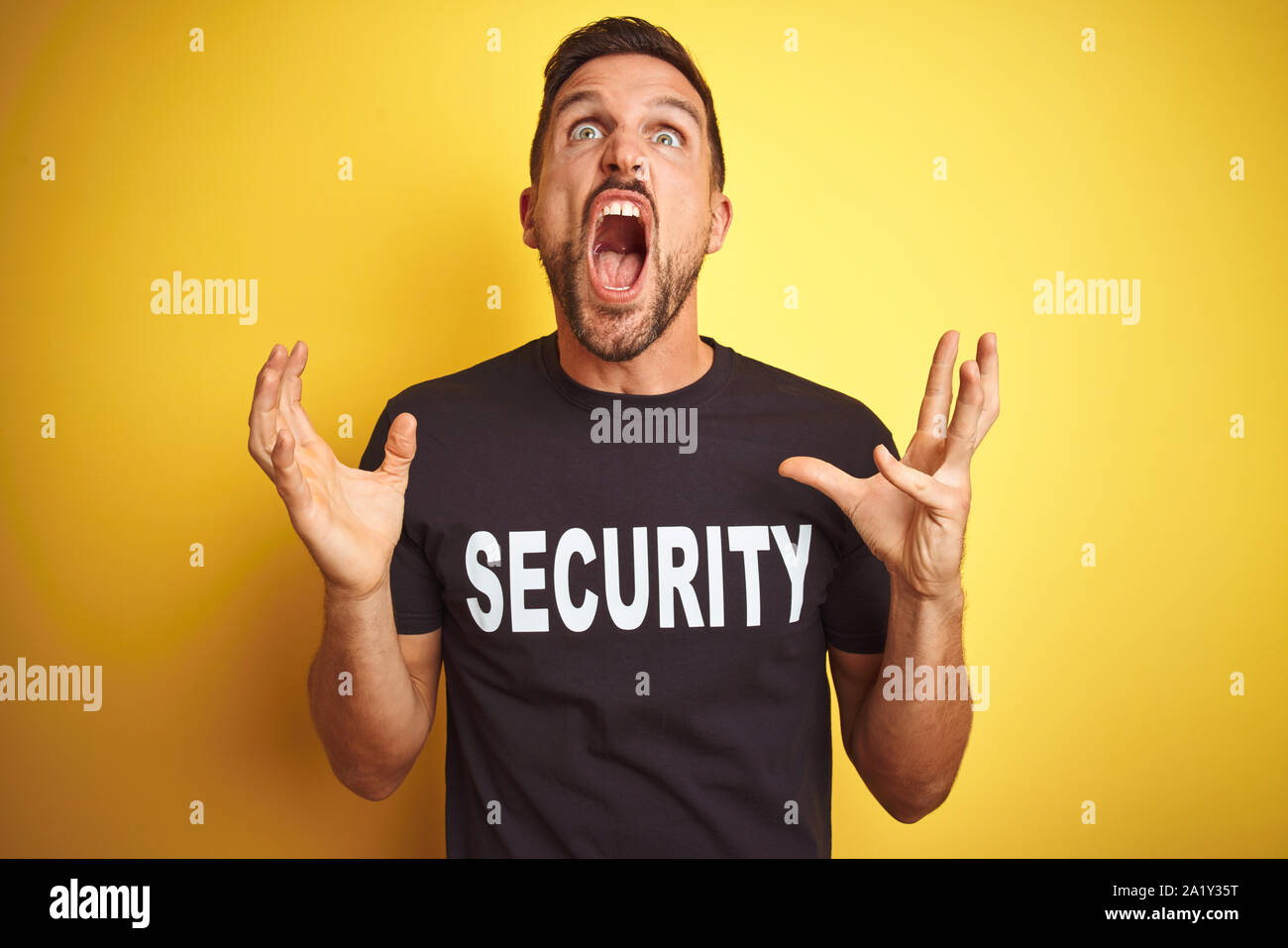Young safeguard man wearing security uniform over yellow isolated ...