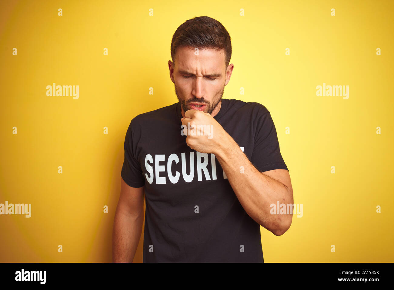 Young safeguard man wearing security uniform over yellow isolated ...