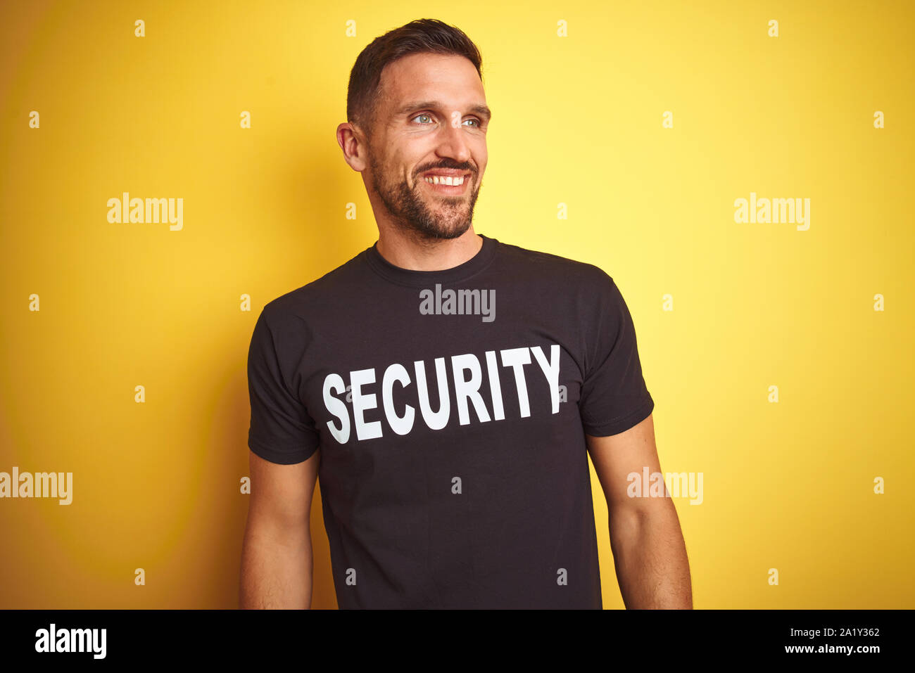 Young safeguard man wearing security uniform over yellow isolated ...