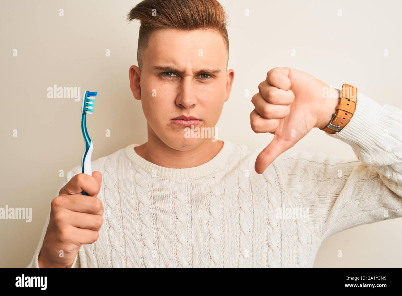 Young handsome man holding tooth brush standing over isolated white ...