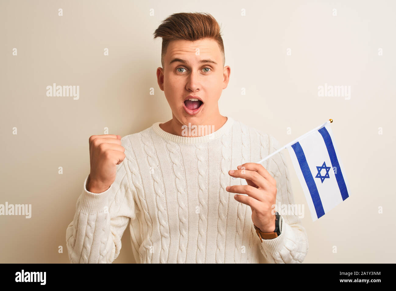 Young handsome man holding Israel Israeli flag over isolated white ...