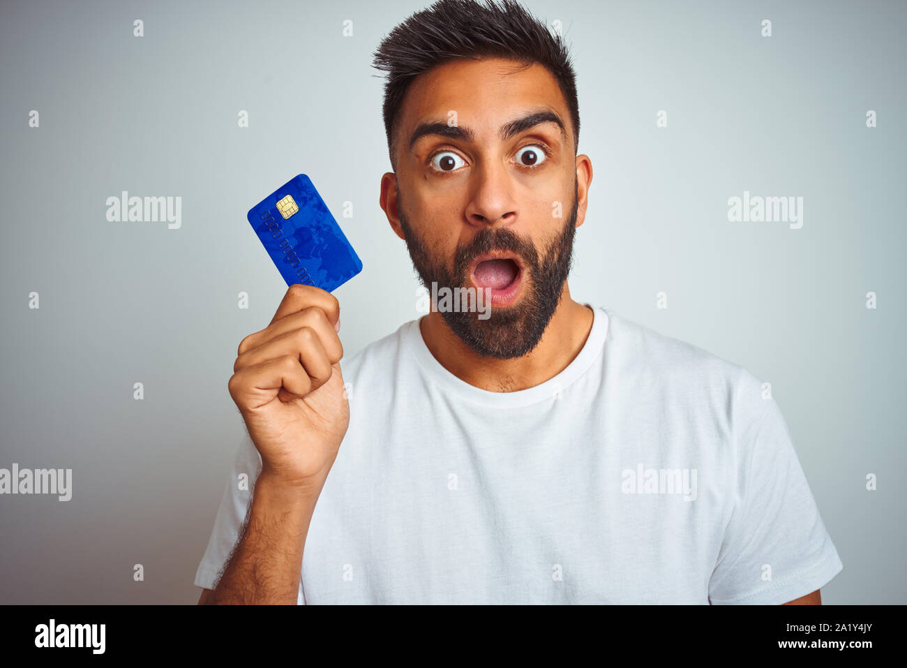 Young indian customer man holding credit card standing over isolated ...