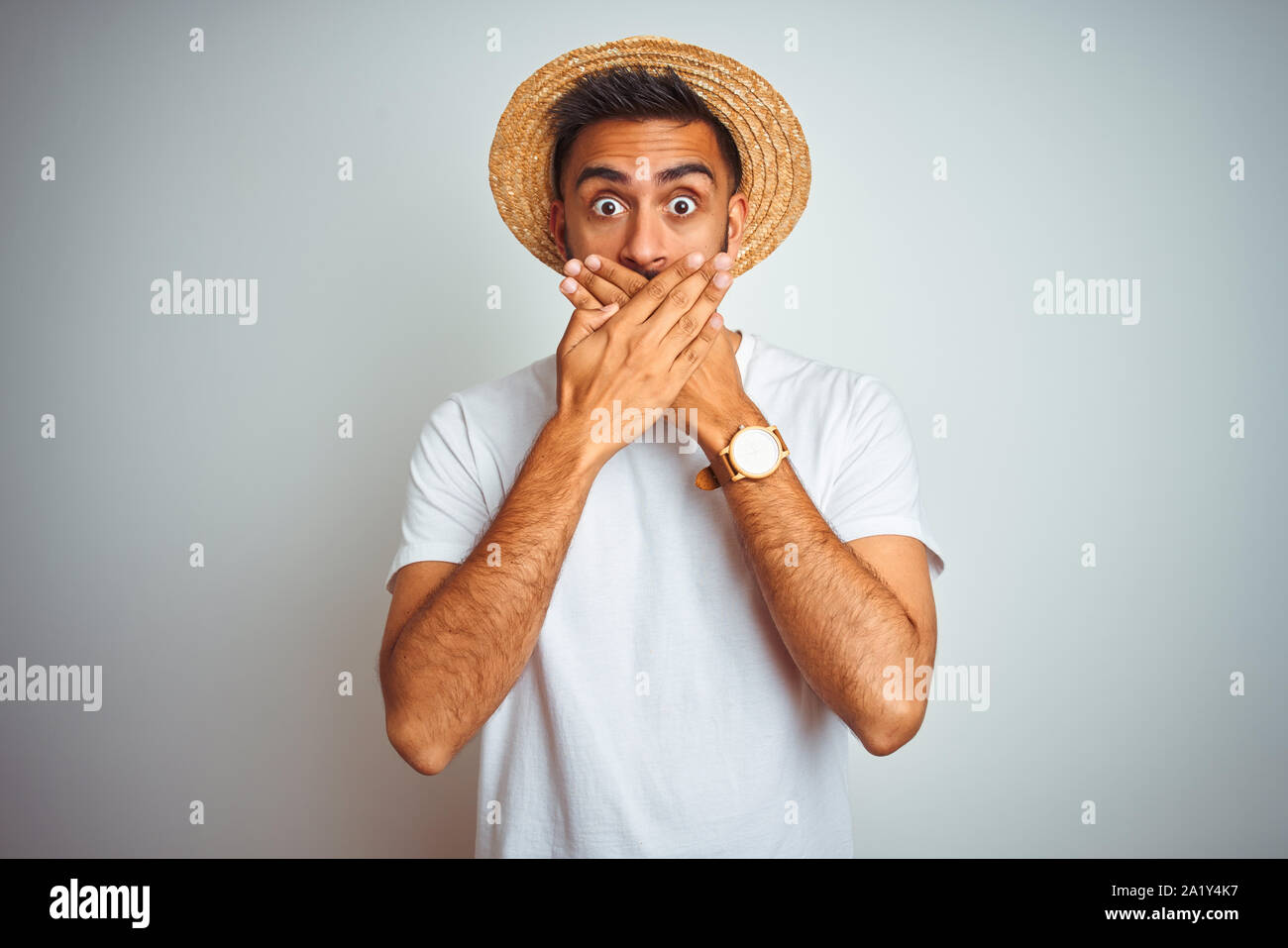 Young indian man on holiday wearing summer hat standing over isolated ...