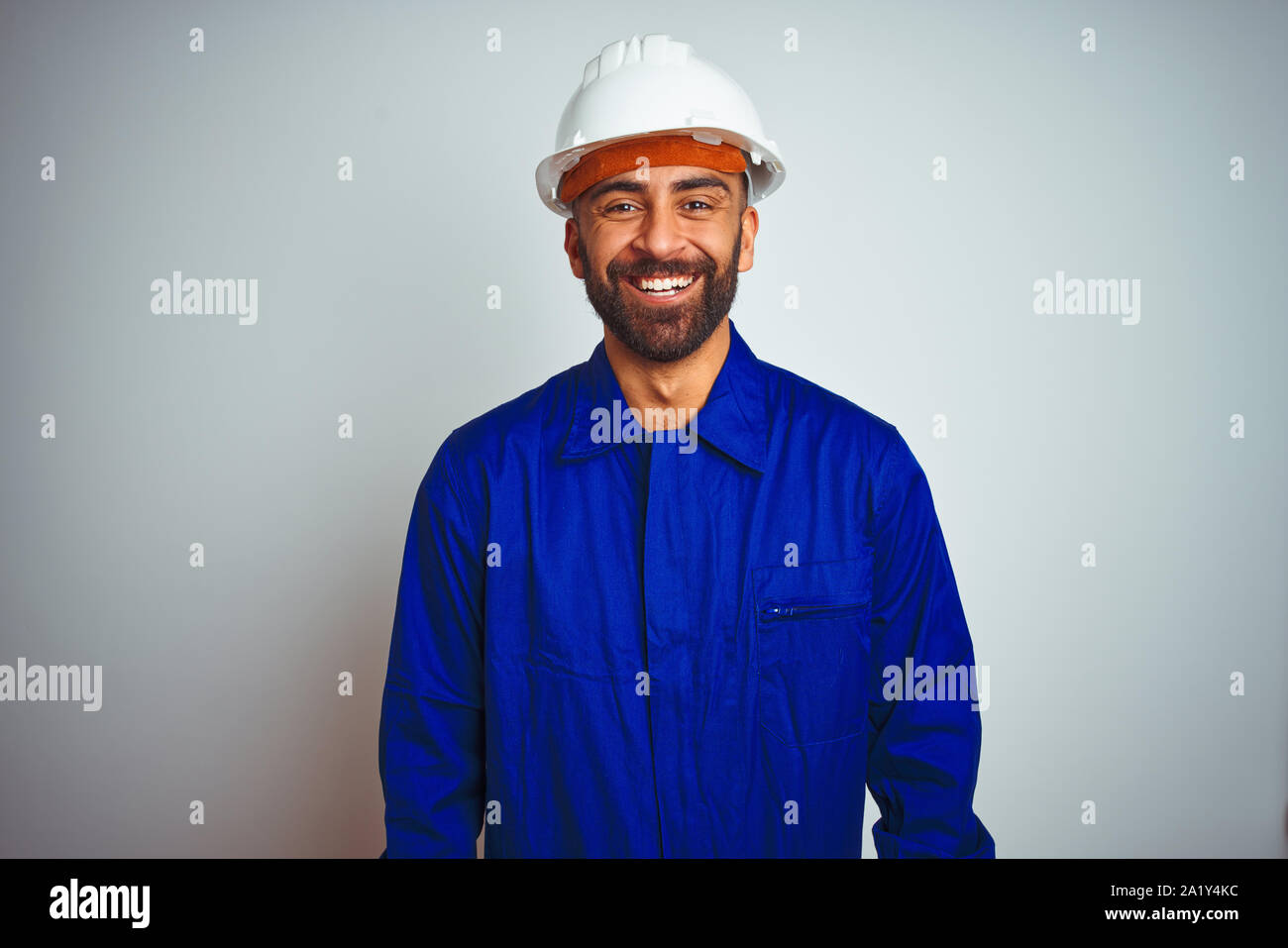 Handsome indian worker man wearing uniform and helmet over isolated ...