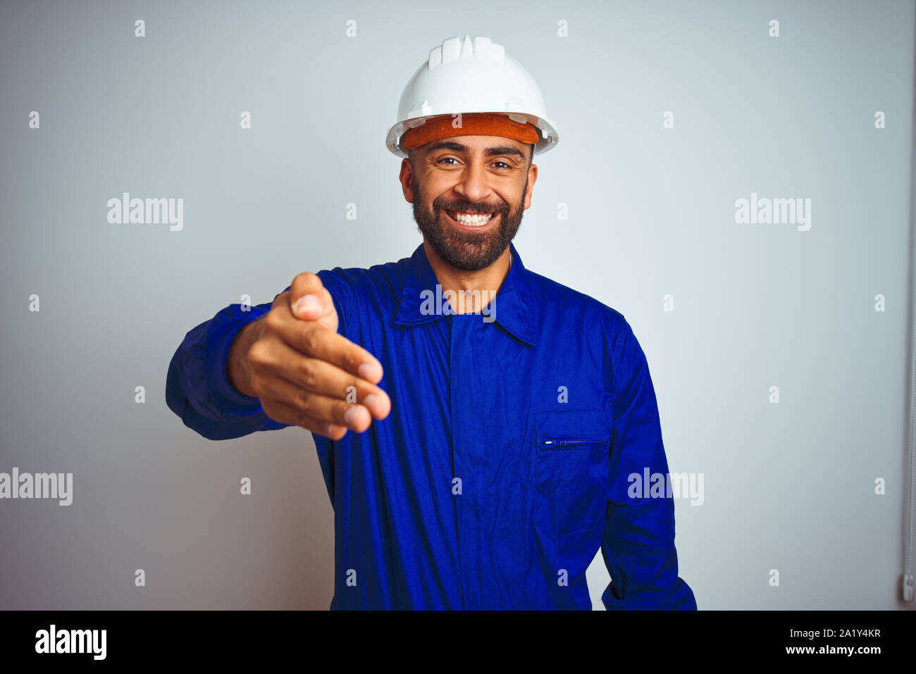 Handsome indian worker man wearing uniform and helmet over isolated ...