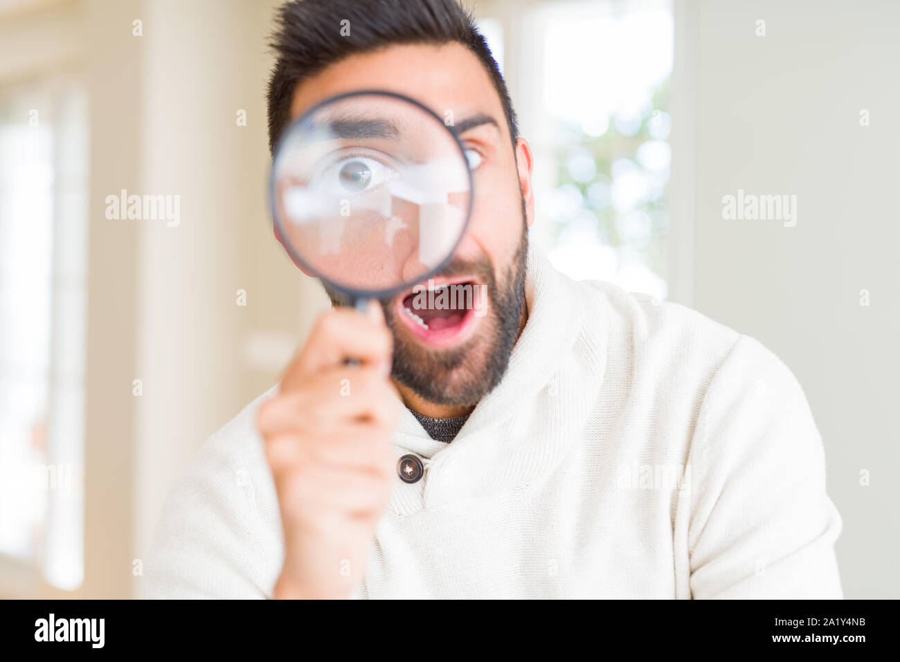 Handsome man using magnifying glass, doing funny faces Stock Photo - Alamy
