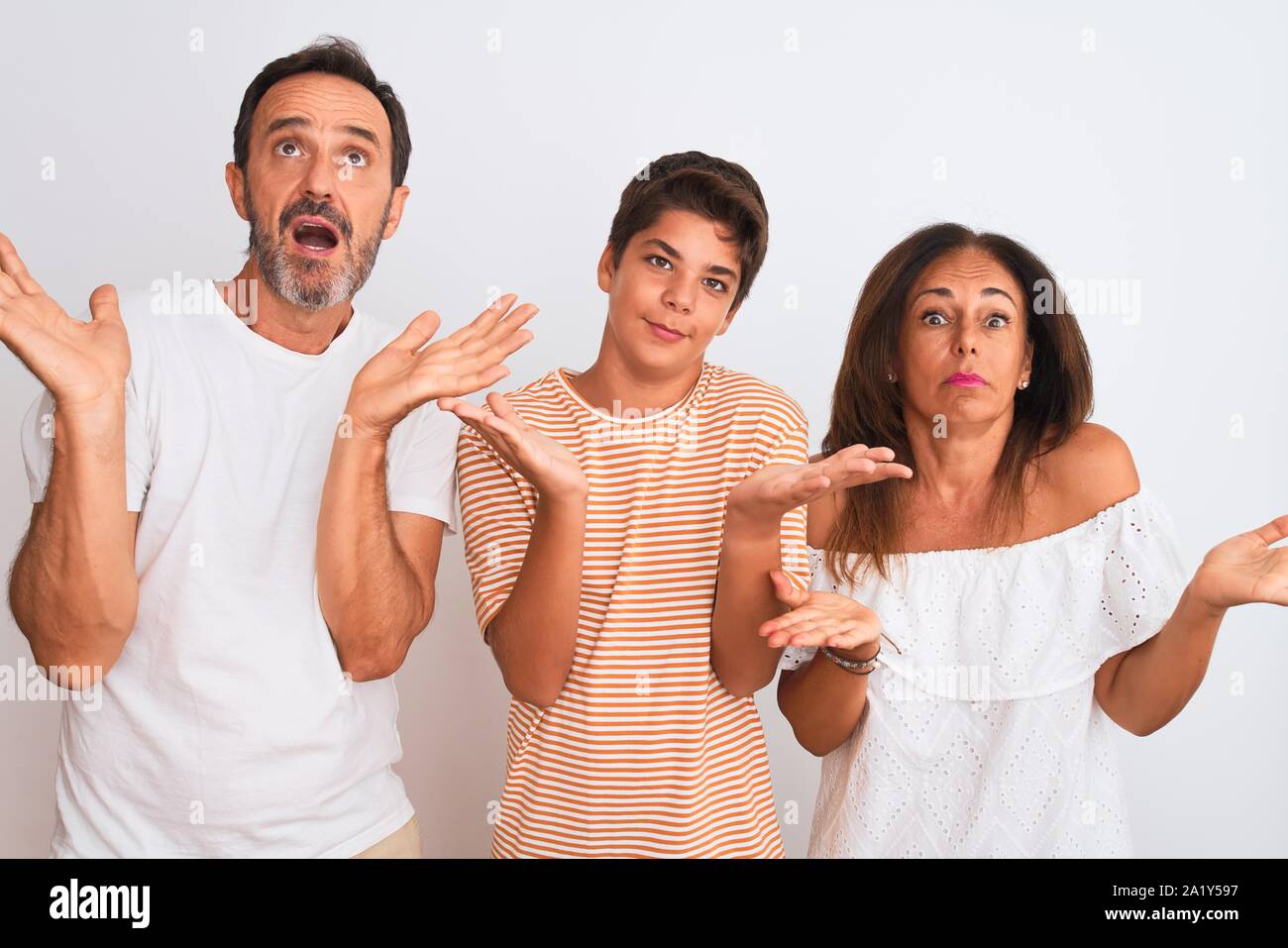 Family of three, mother, father and son standing over white isolated ...
