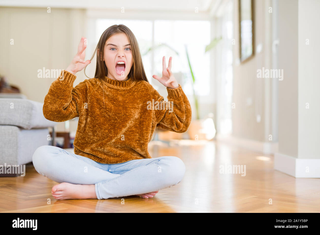 Beautiful young girl kid sitting on the floor at home crazy and mad ...