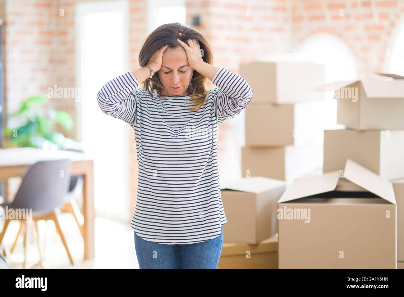 Middle age woman moving to a new house arround cardboard boxes ...