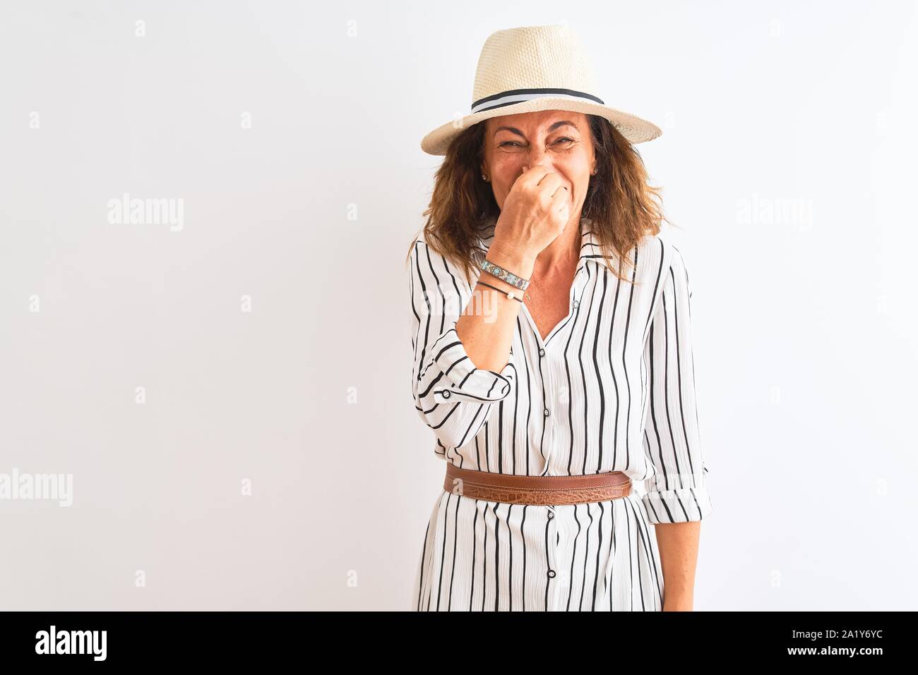 Middle age businesswoman wearing striped dress and hat over isolated ...