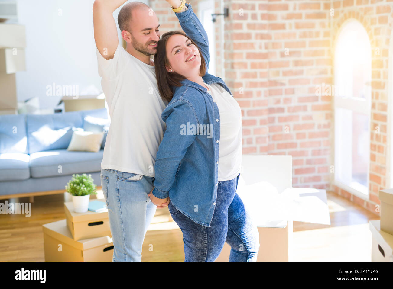 Young couple dancing around cardboard boxes at new home, celebrating ...