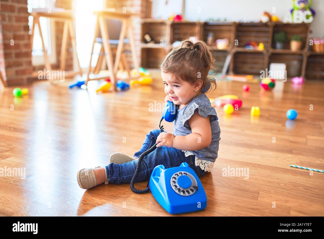 Beautiful toddler sitting on the floor playing with vintage phone at ...