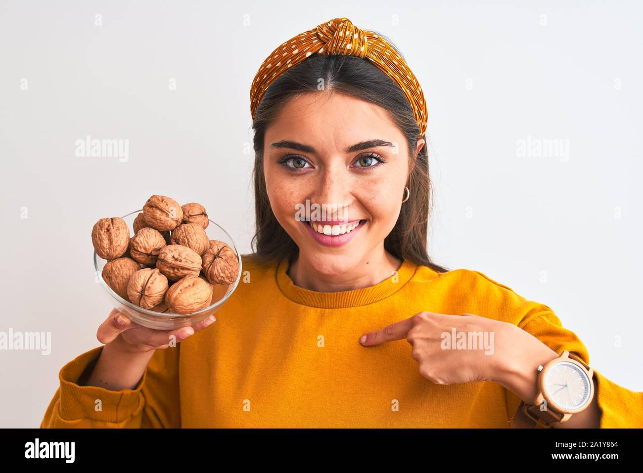 Young beautiful woman holding bowl with walnuts standing over isolated ...