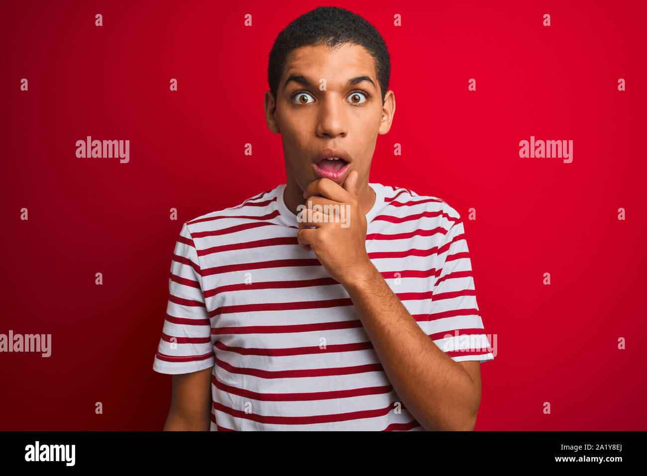 Young Handsome Arab Man Wearing Striped T Shirt Over Isolated Red