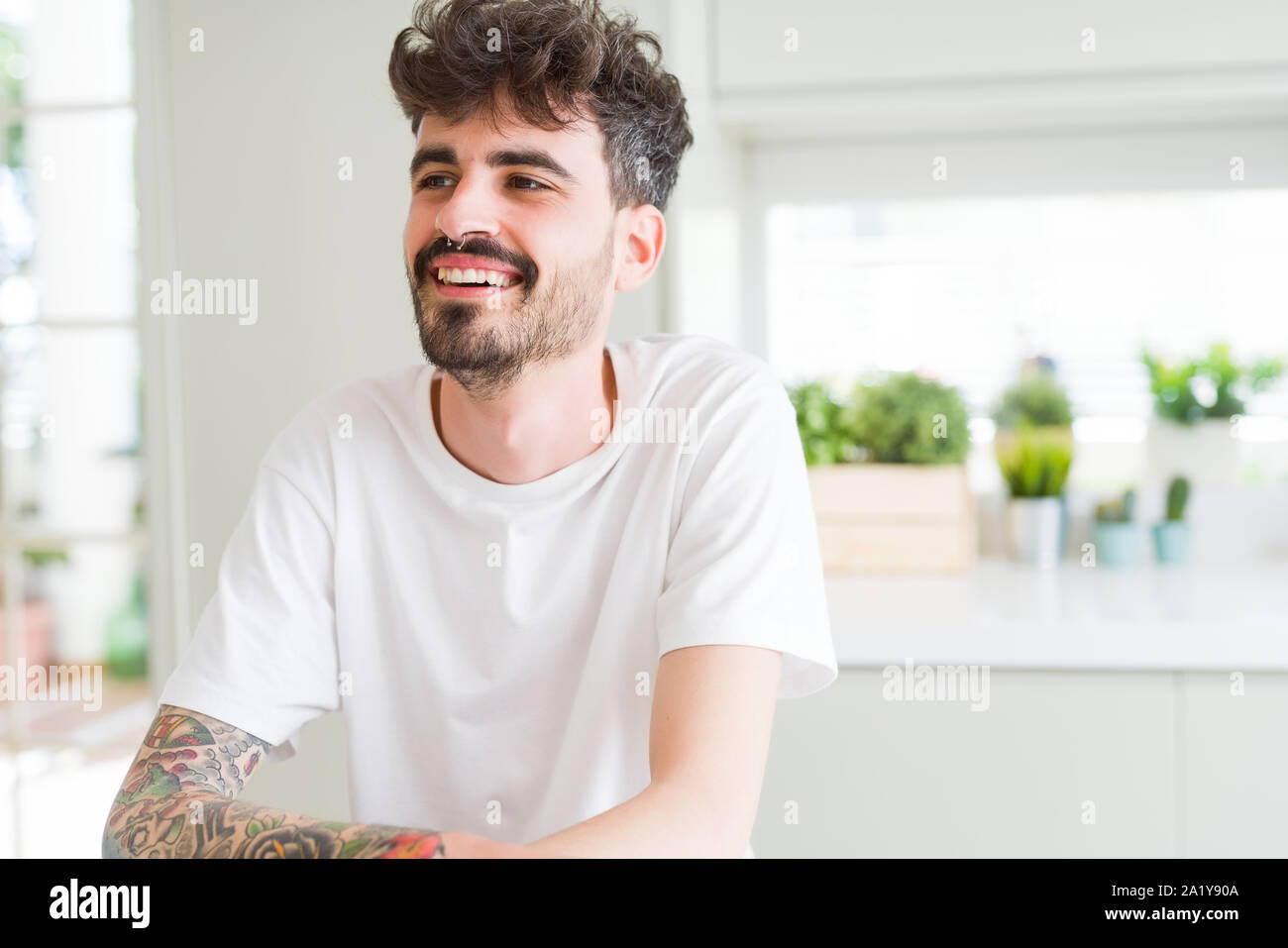 Handsome young man smiling cheerful at the camera with crossed arms and ...