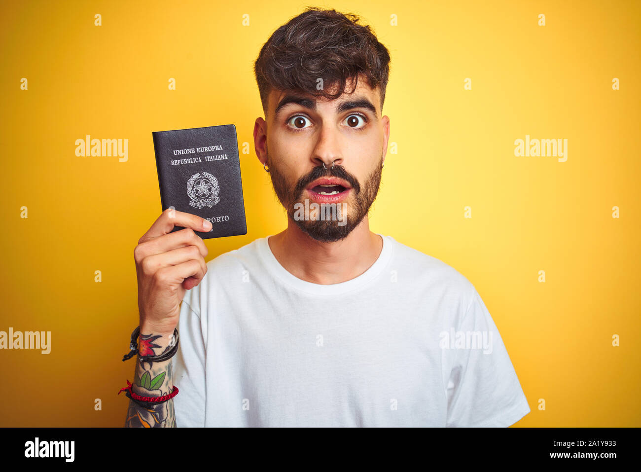 Young man with tattoo wearing Italy Italian passport over isolated ...