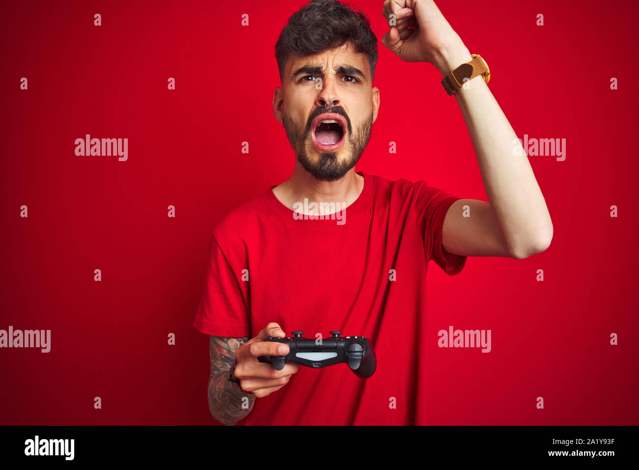 Young gamer man with tattoo playing video game standing over isolated ...