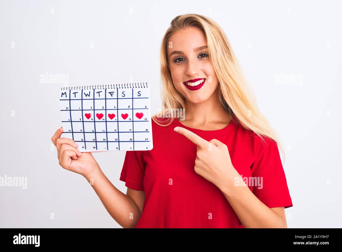Young beautiful woman holding period calendar standing over isolated ...