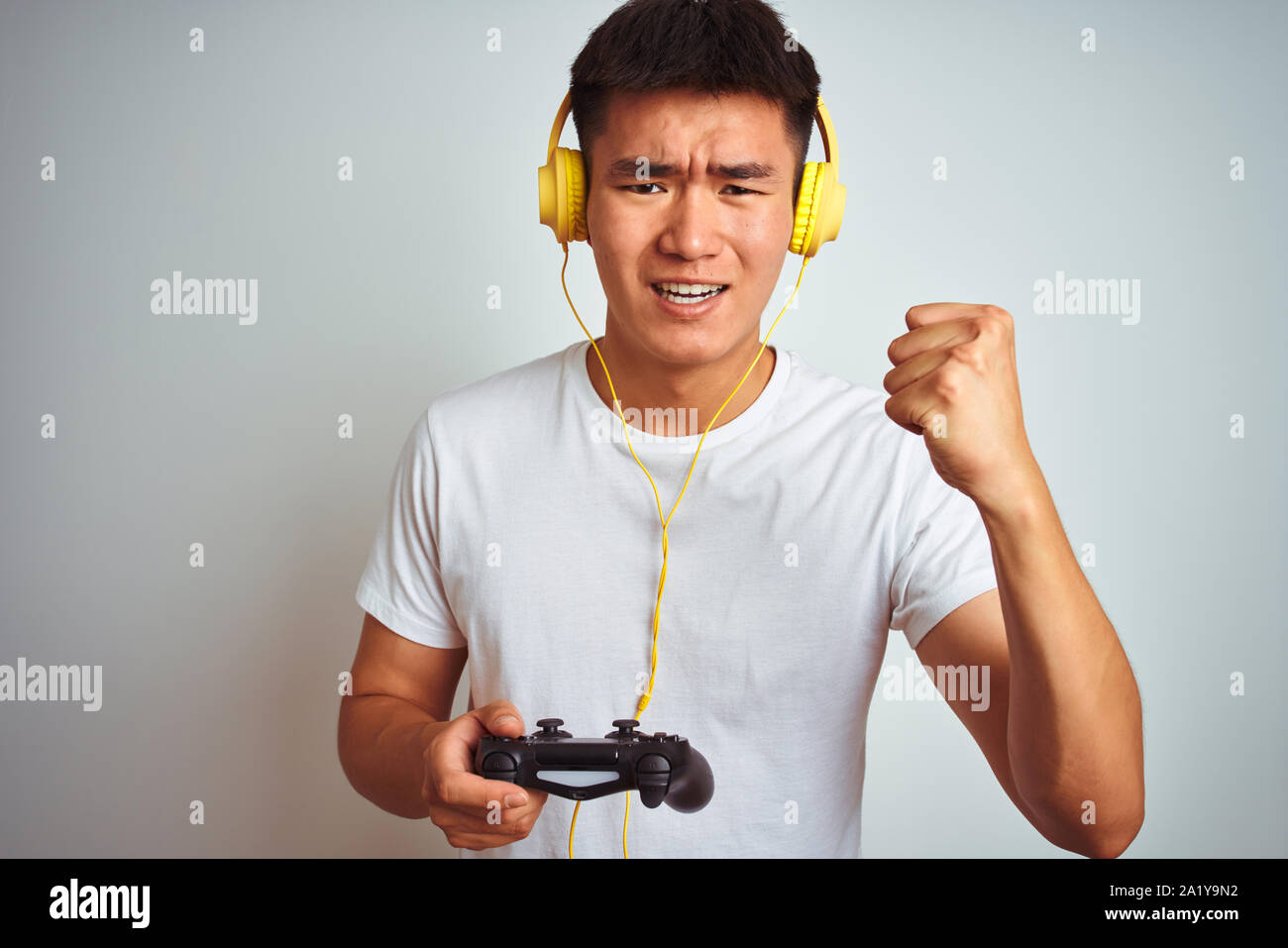 Young asian chinese gamer man playing video game standing over isolated ...