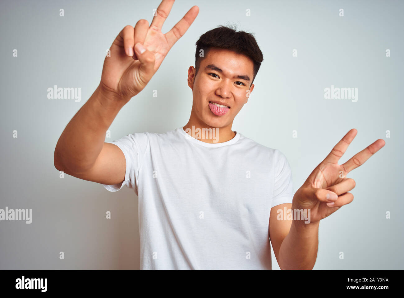 Young asian chinese man wearing t-shirt standing over isolated white ...
