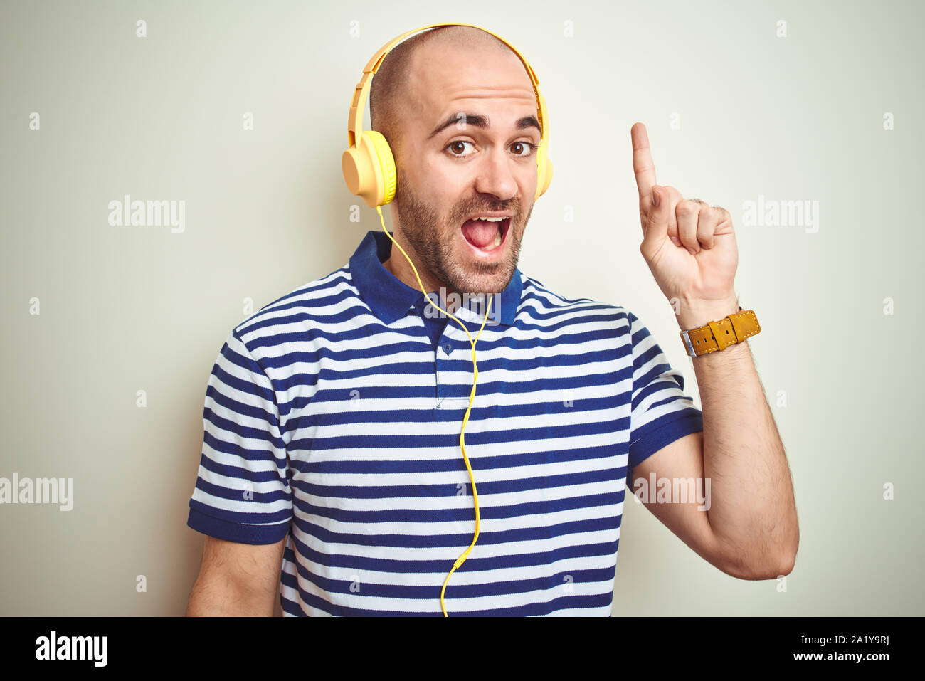 Young man listening to music wearing yellow headphones over isolated ...