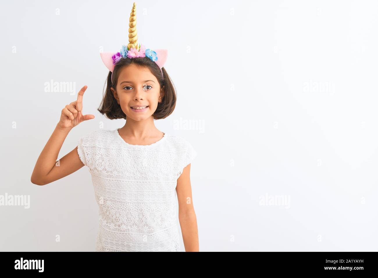 Beautiful child girl wearing unicorn diadem standing over isolated ...